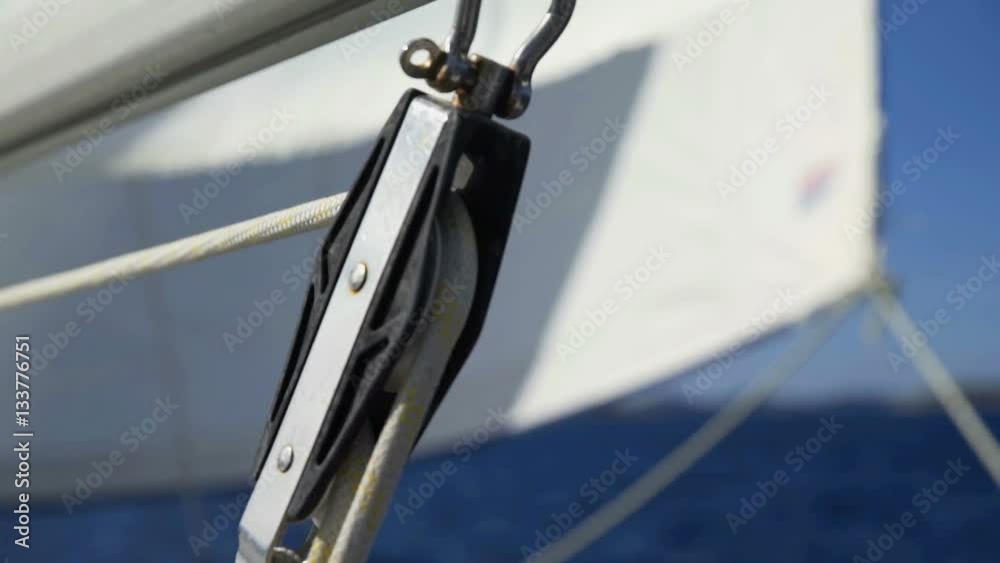 We can see a pulley system on a sailing boat. We can see a rope that is ...