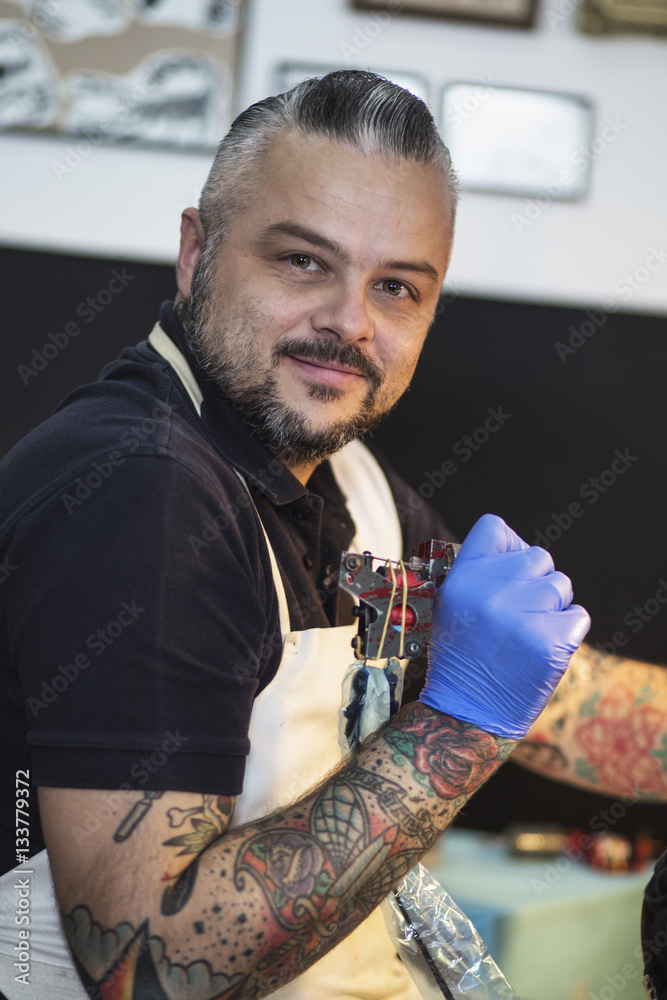 Guy is making tattoo, in a studio. Young man artist tattooing on the ...