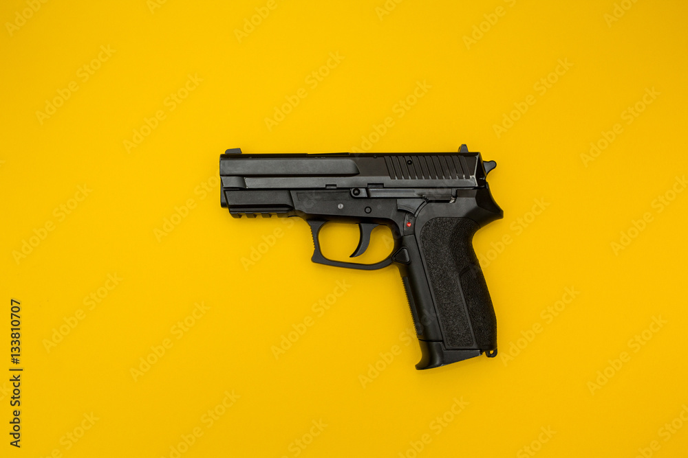 Black gun on a yellow background, concept Stock Photo | Adobe Stock