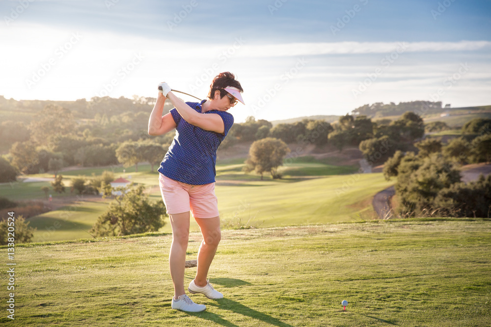 Mature woman playing golf. Golfer hitting golf shot with driver club on ...