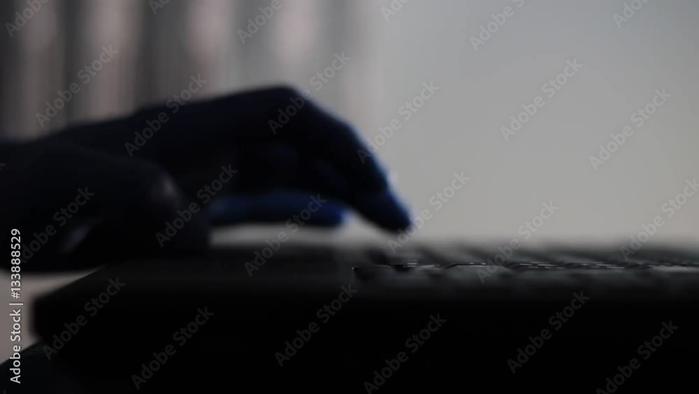 Shadow, silhouette of a male palm hand, typing on the laptop keyboard ...