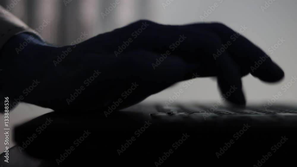 Shadow, silhouette of a male palm hand, typing on the laptop keyboard ...