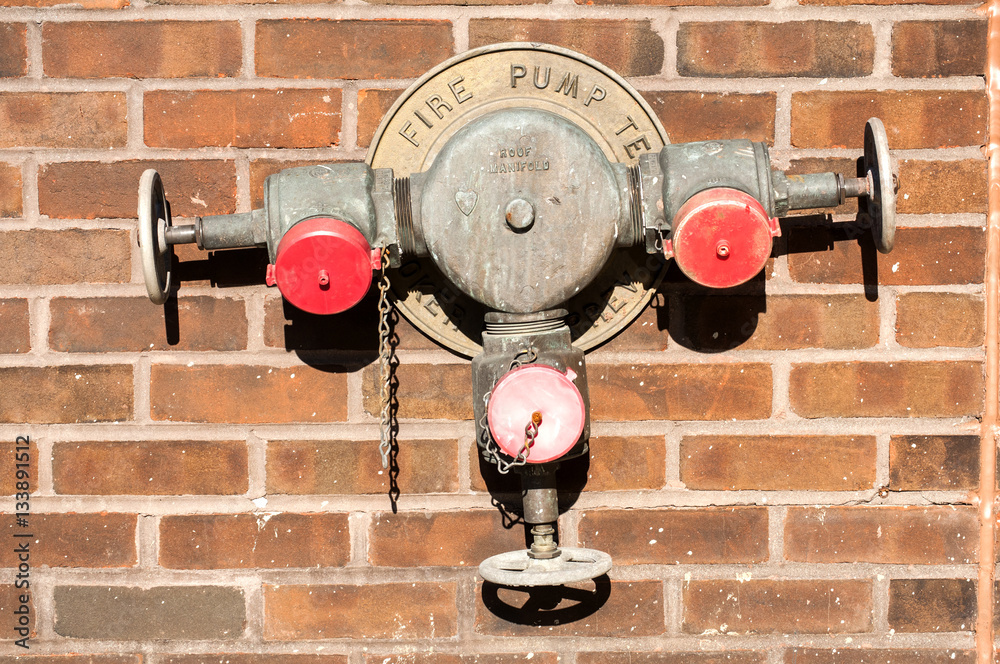 Fire hydrant with tree valves mounted on red brick house wall Stock ...