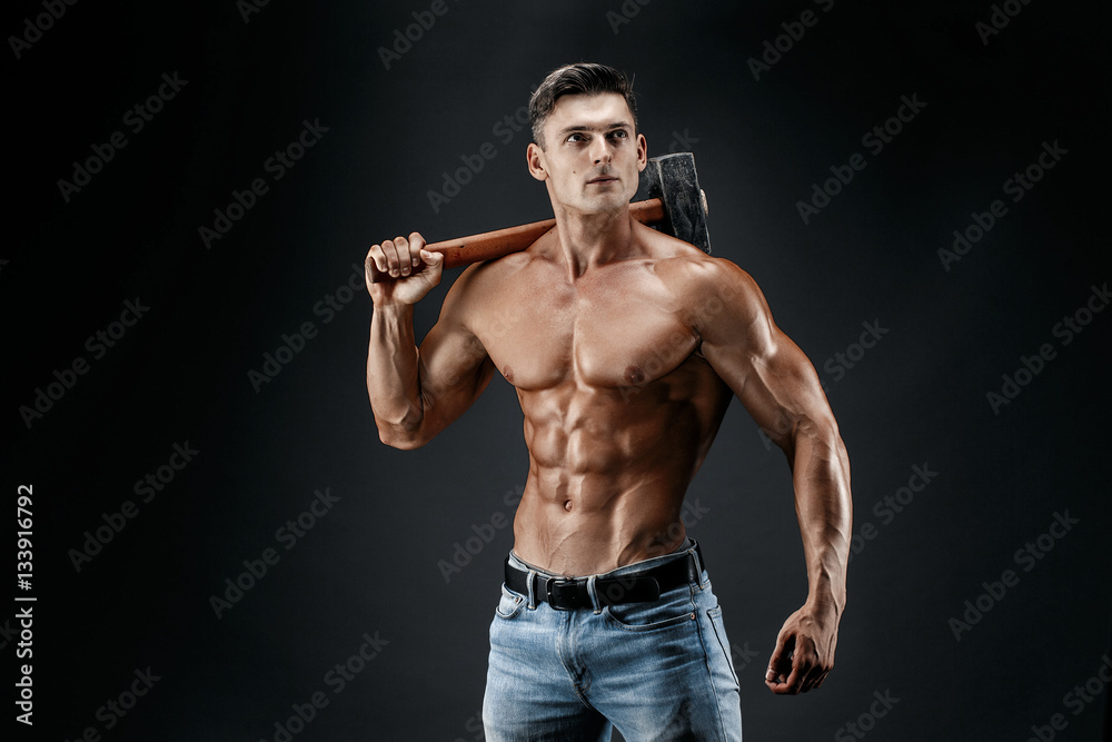 Muscular man with naked torso holding big hummer. Isolated on dark grey ...