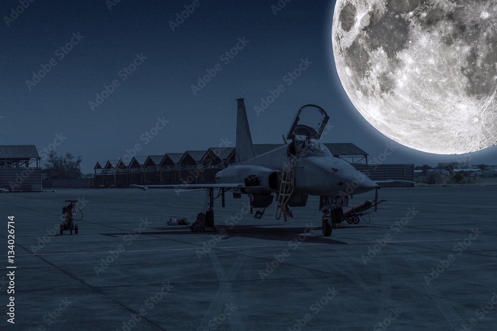 F-5E Aggressor Hornet fighter jet reflects the full moonlight. F-5 military aircraft parked in ...
