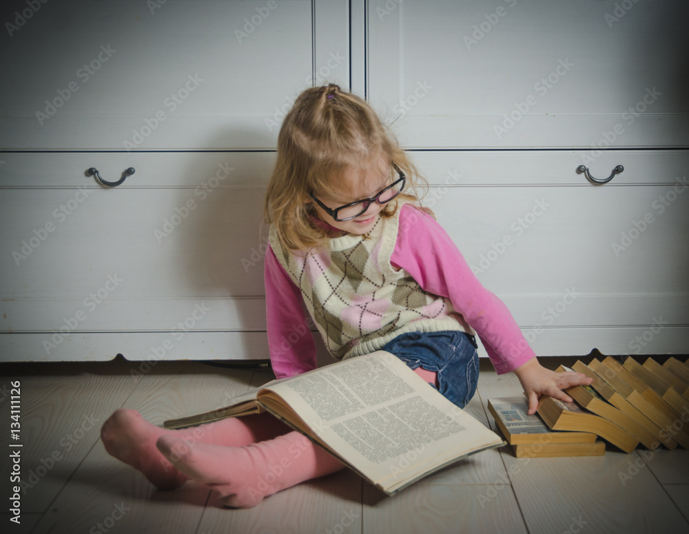on the floor with a book on your feet kid girl with glasses. Stock ...