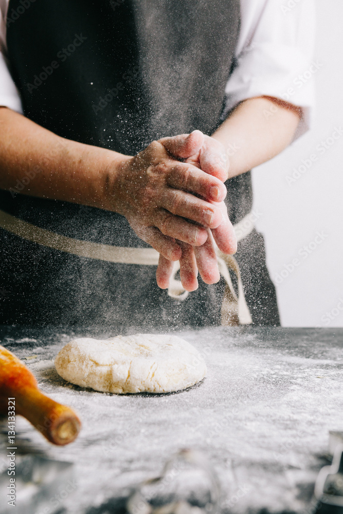 Cook covering hands with flour for beating up a cookie pastry. Vertical ...
