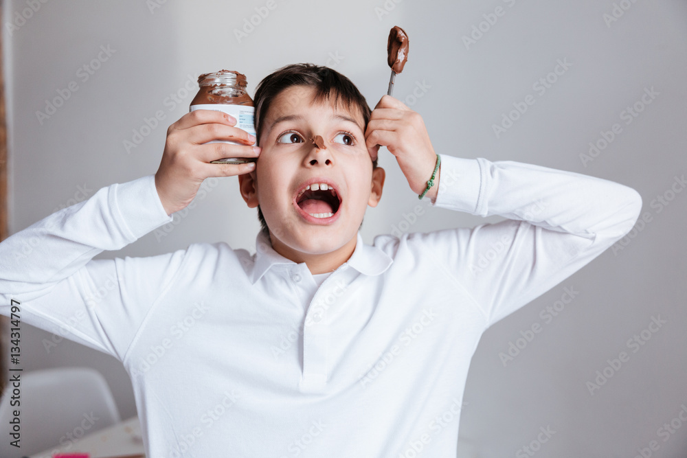 Amusing little boy eating chocolate spread from jar and shouting Stock ...