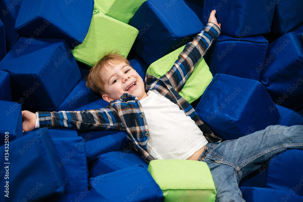 Cheerful little boy lying in pool with soft cube pillows Stock Photo ...