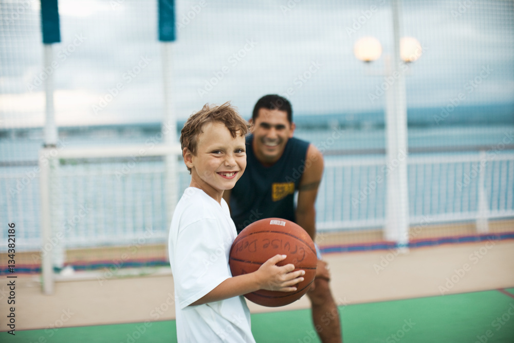 Boy holding a basketball and his basketball tutor smile in the ...