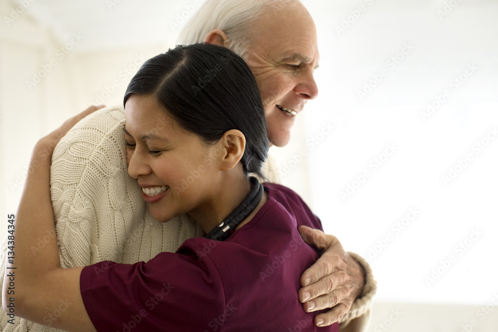Smiling female nurse hugging an elderly male patient. Stock Photo ...