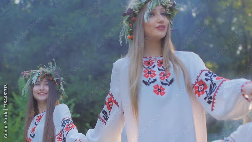 a group of young people in national Slavic costumes dance in a circle ...