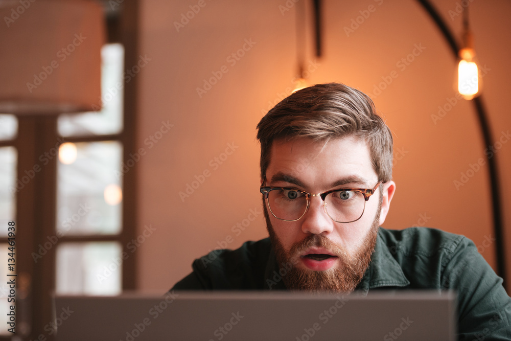 Confused bearded young man using laptop computer. Stock Photo | Adobe Stock