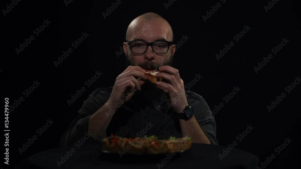 Hungry man eating a sandwich on a black background. Stock Video | Adobe ...