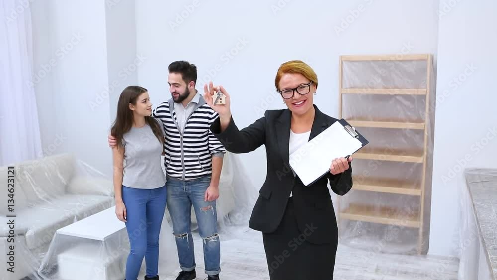 Happy real estate agent woman showing apartment or flat to young couple ...