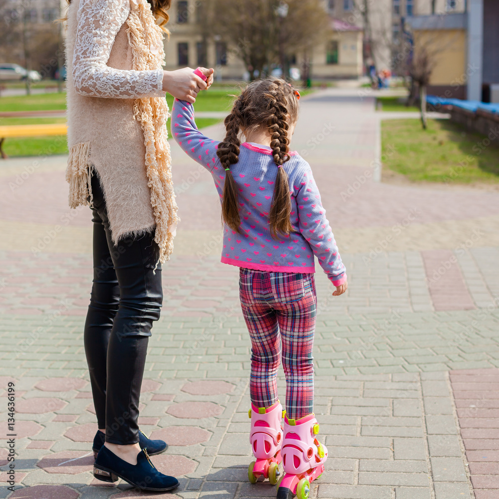 Mom and daughter ride on roller skates. Girl learning to roller skate ...