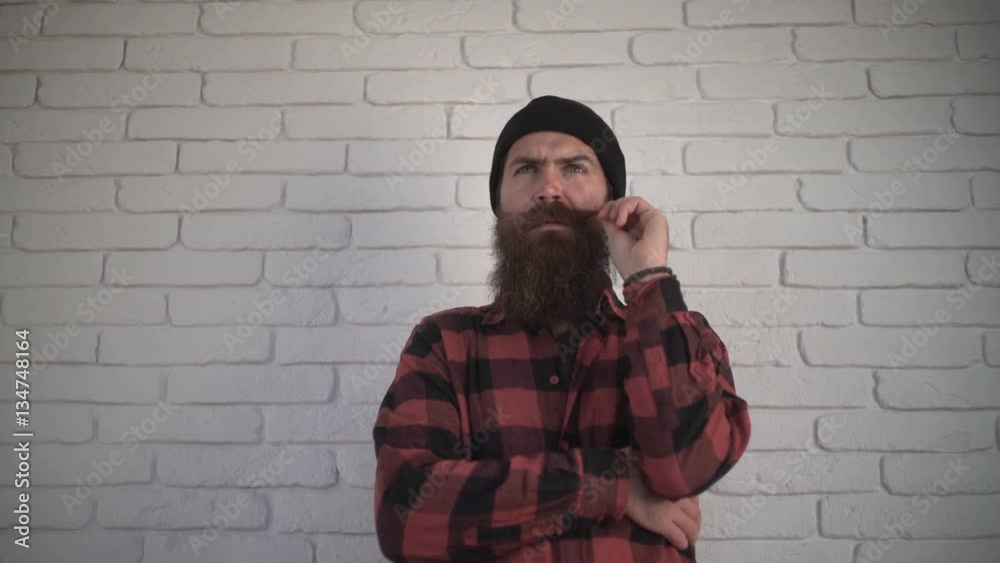 Thoughtful man with a beard stroking his beard, mustache twirling and ...