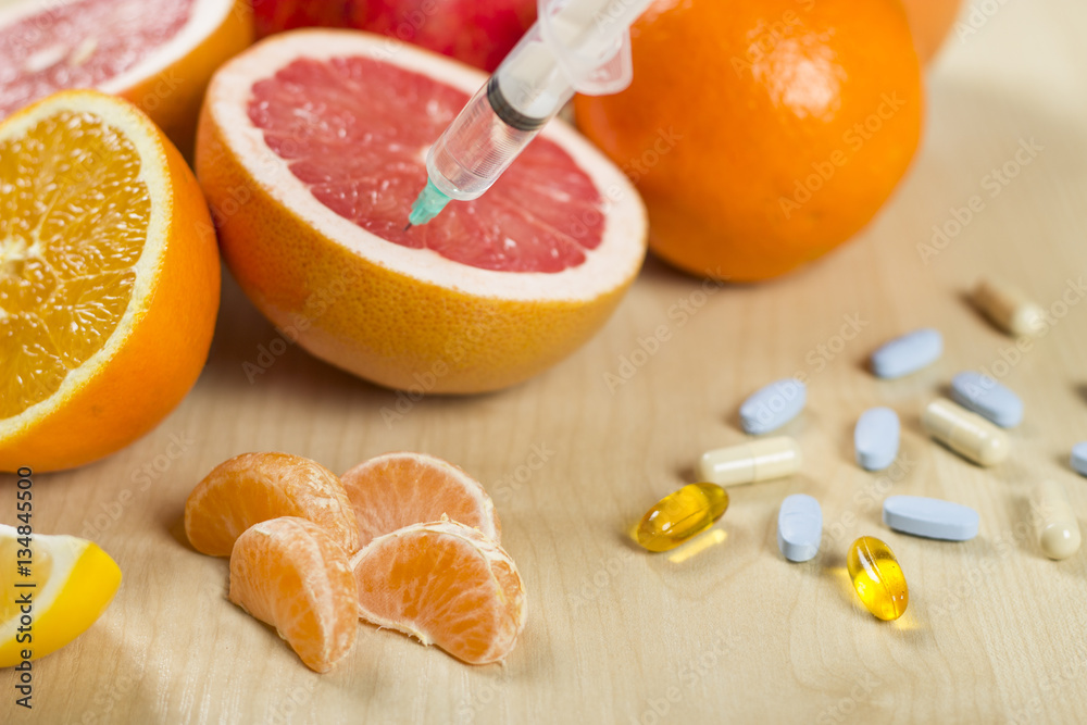 Needle and syringe injected in the fruit. Nutrition concept. Enhanced ...