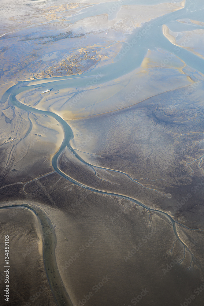 aerial view of the mudflat coastline at low tide with water winding in the mud and sand bank ...