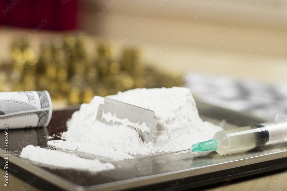 Close-up of a digital scale with a cocaine pile on it and a razor blade ...