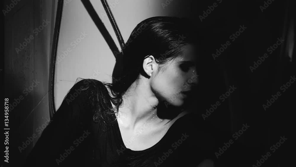 Sad woman crying in shower with water falling on her black and white ...