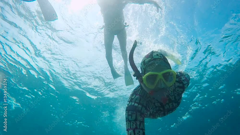 Couple of tourists in swimwear and flippers diving in the ocean near ...