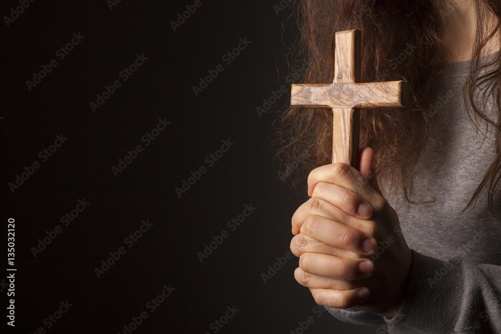 Hands with cross on dark background Stock Photo | Adobe Stock