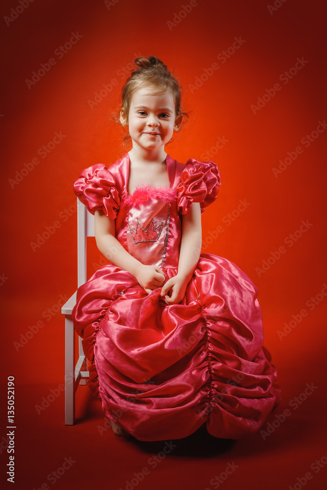little princess sitting on a chair on a red background Stock-Foto ...