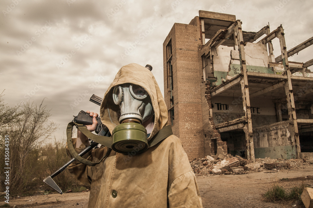 young boy stands with a gun in his hand. boy in a gas mask. boy in a ...