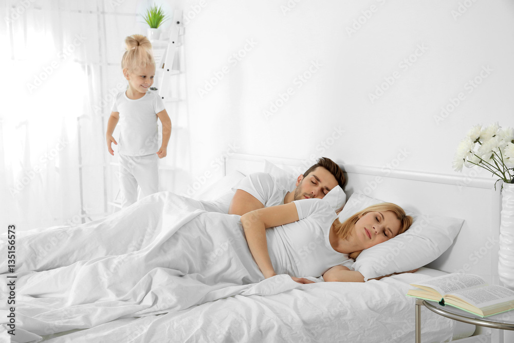 Cute little girl going to wake up her parents sleeping in bed Stock ...