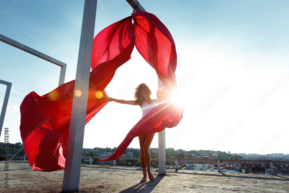 Beautiful brunette silk dancer with red curtains posing at rooftop ...