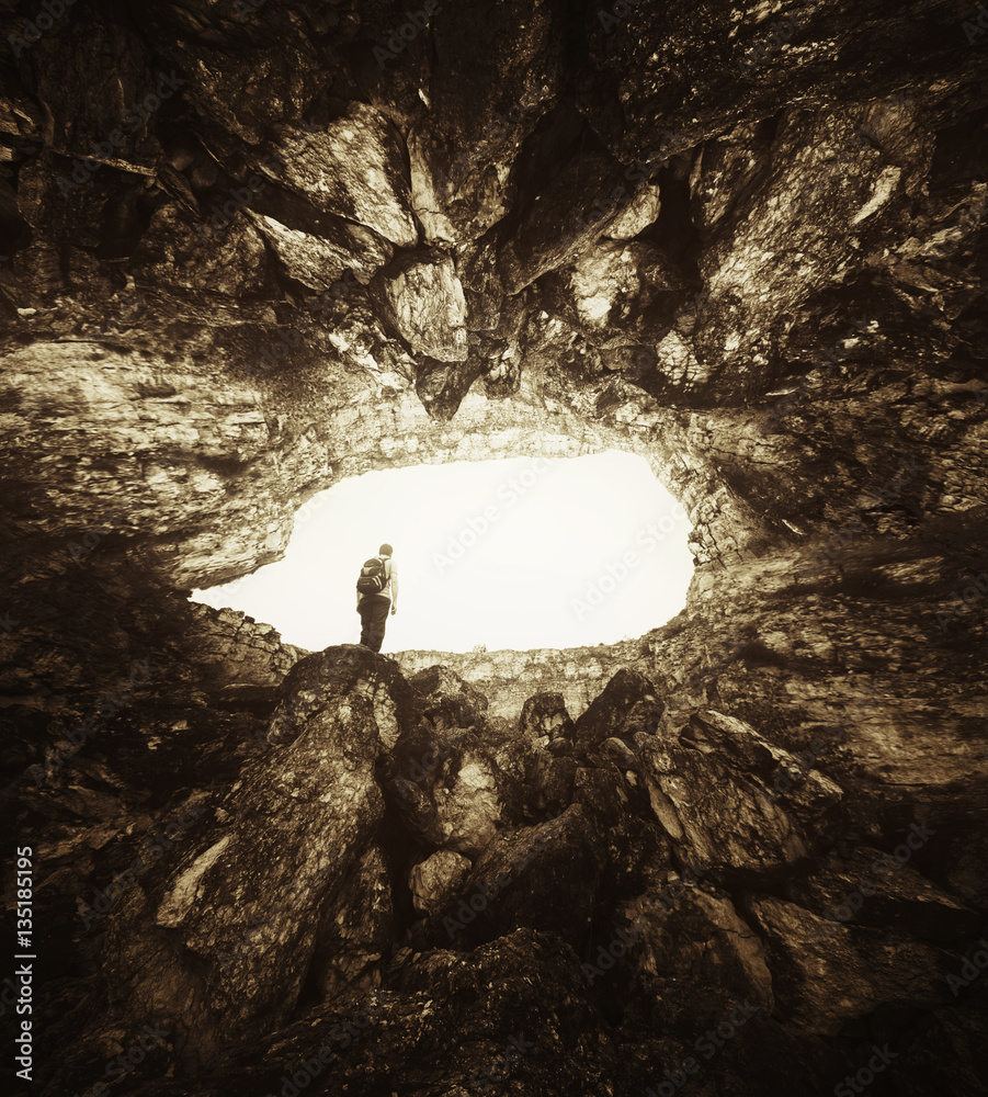 Man at cave entrance. Underground landscape with light entering dark ...