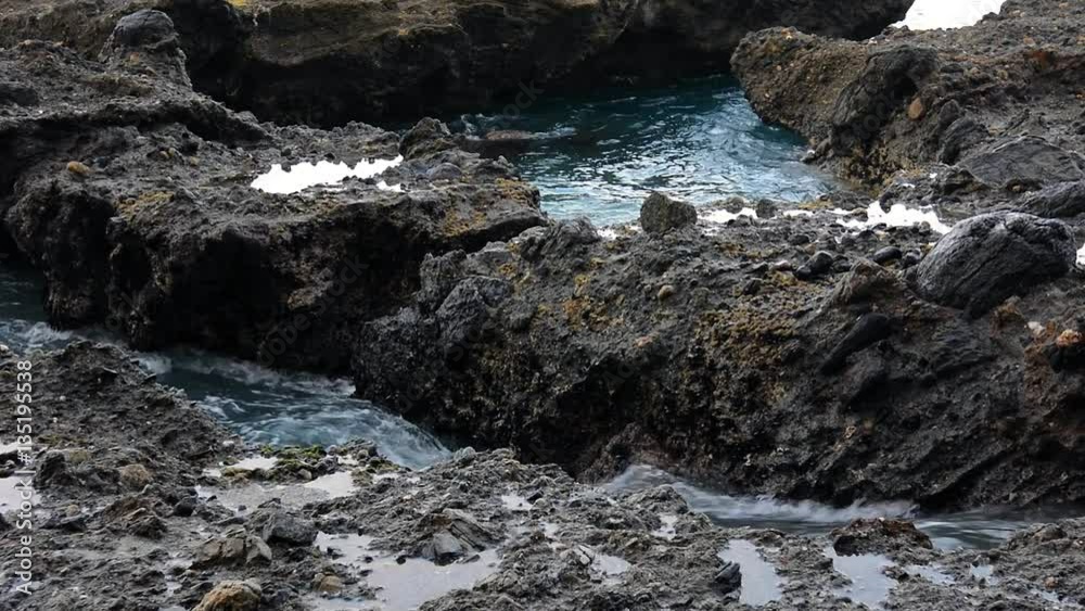 Pan of an ocean reef crevice with water powering through the canyons ...