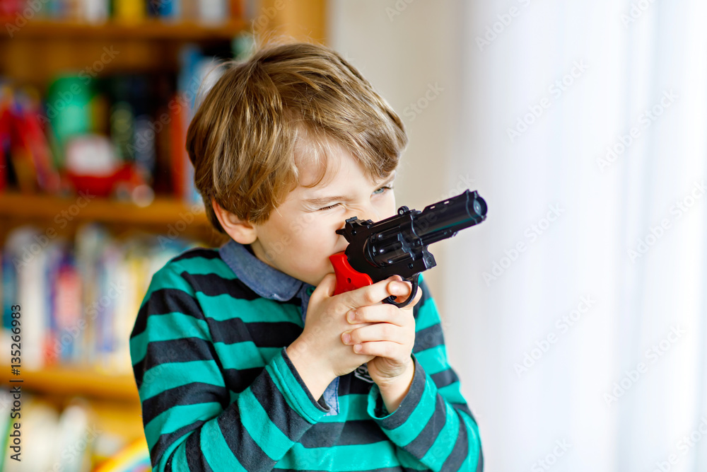Cute little preschool kid boy playing with gun at home, Stock Photo ...