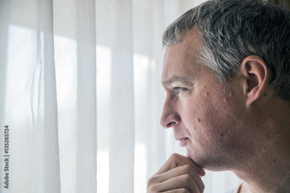 Sad man looking out the window. Feeling hopeless. Depressed mature man ...