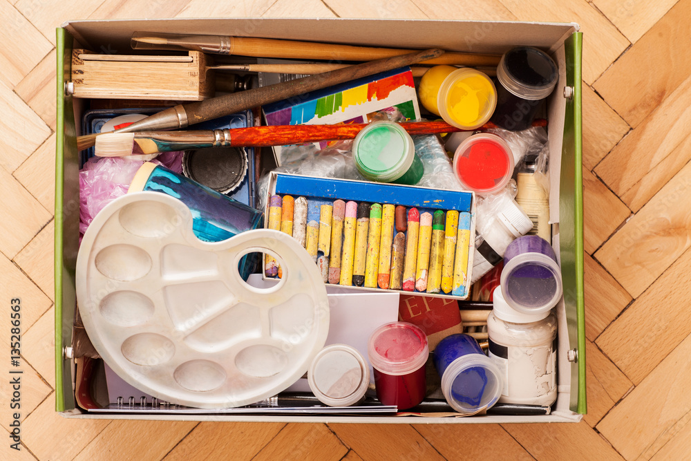 Crayons, gouache, paint brushes, pallet and other drawing stuff folded ...