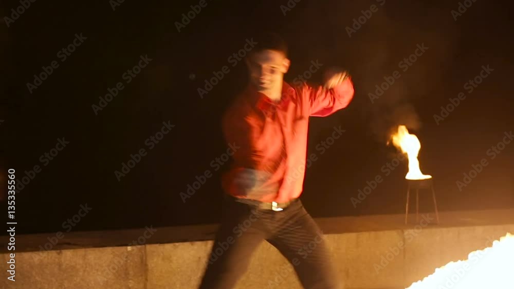 Artist man rotates the fireball.Man twist fiery circles on a fire show ...