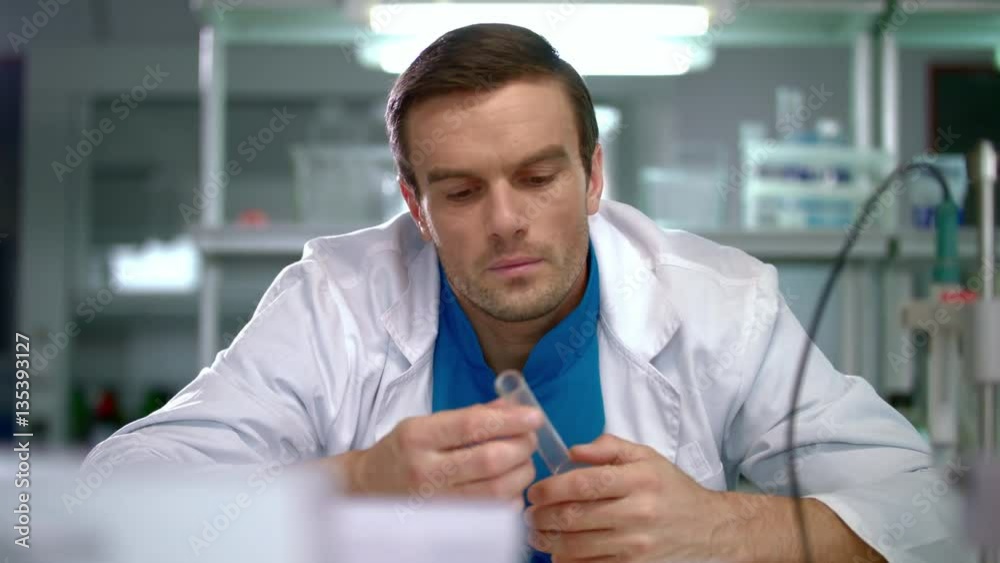 Researcher checking flask. Researcher blowing in glass flask ...