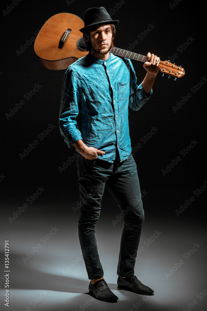 Cool guy standing with guitar on dark background Stock Photo | Adobe Stock