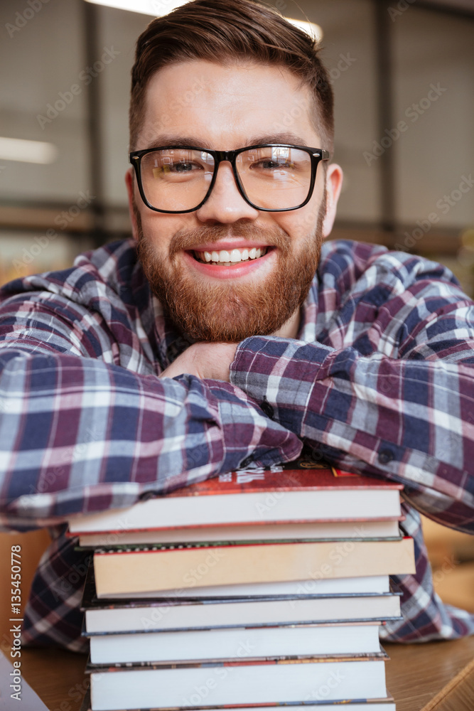 Smiling male student resting on stack of books Stock Photo | Adobe Stock