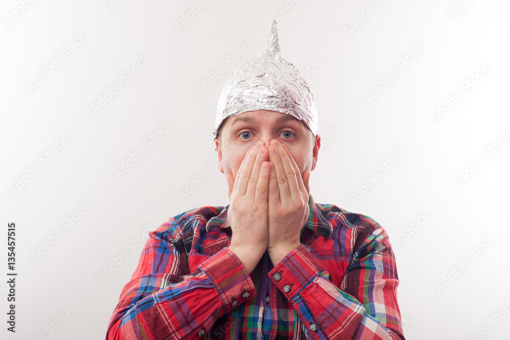 young man in a tin foil hat poses funny faces. Afraid of radiation or ...