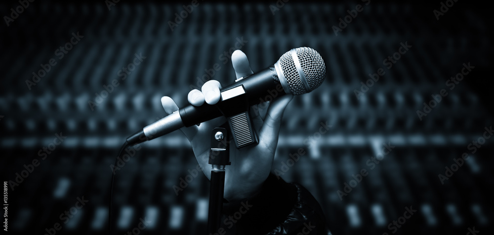singer hands holding microphone on studio mixer background. hands sign ...