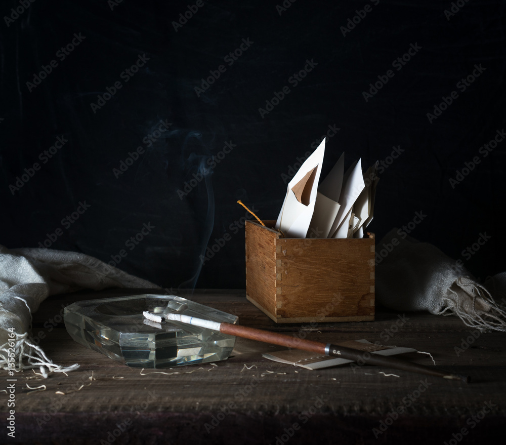 Still Life with a box of letters, and smoking a cigarette. dark ...