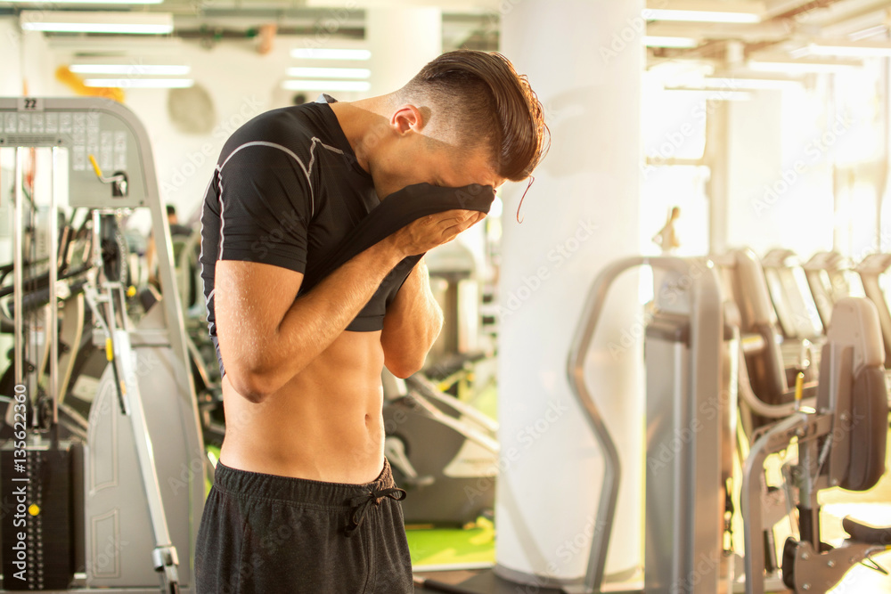 Athletic man wiping sweat after hard workout in gym. Stock Photo ...