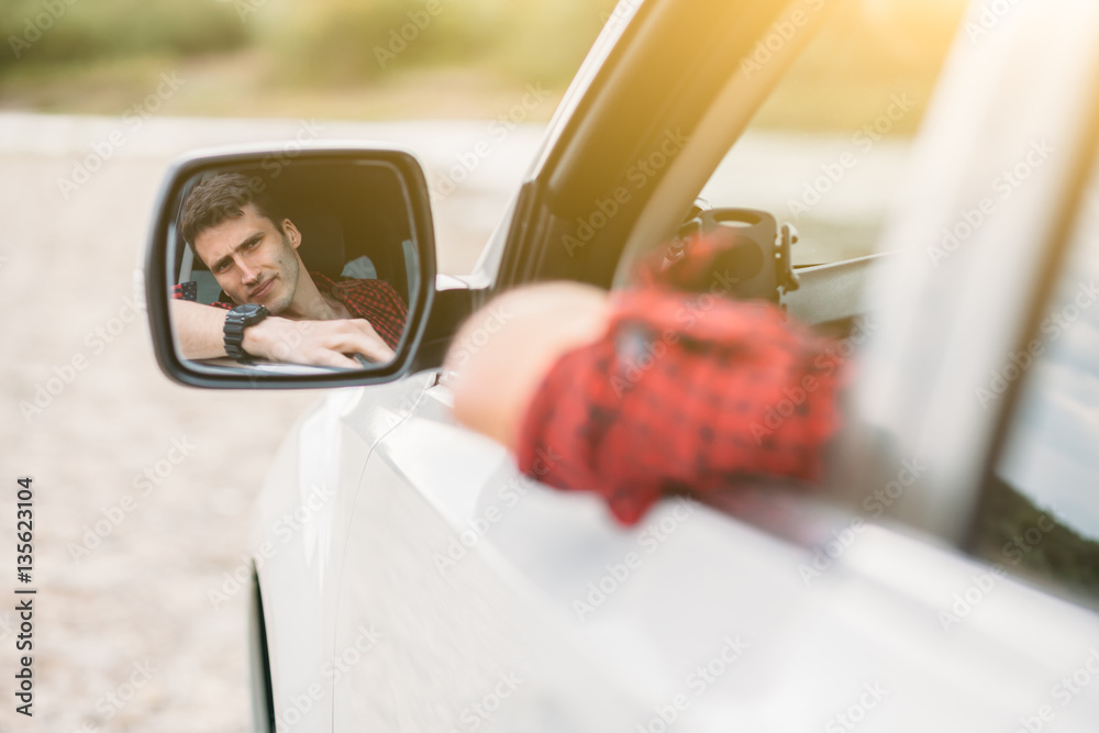 Young man driver looking in car side view mirror, making sure line is ...