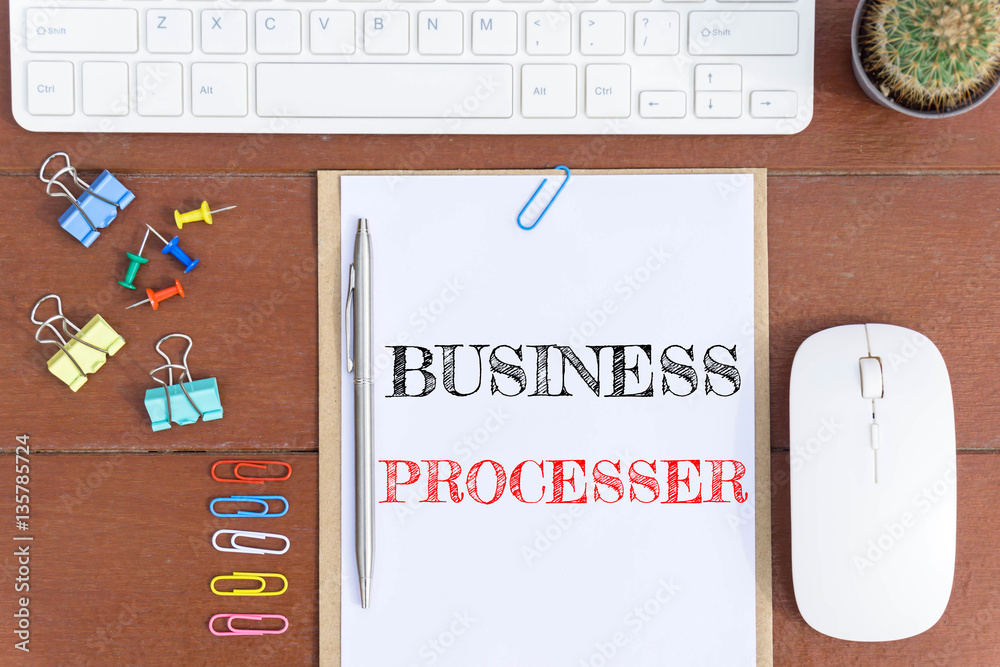 Text Business Processor on white paper which has keyboard mouse pen and office equipment on wood ...