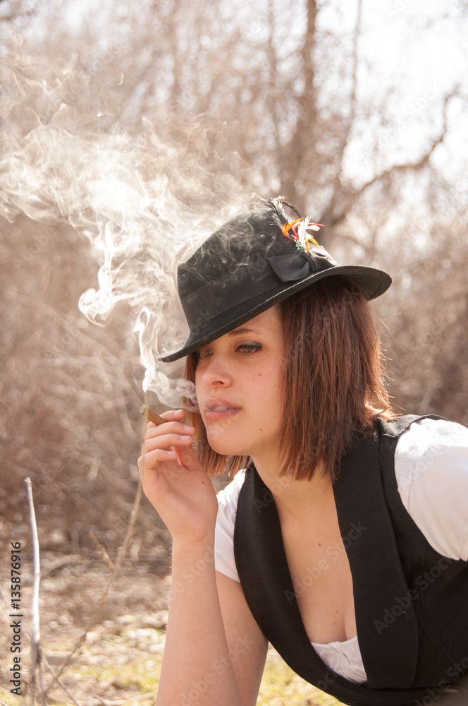 Young woman smokes cigar outside in the countryside. Cigar smokes ...