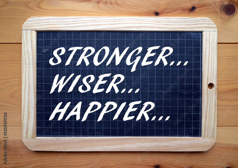 The words Stronger, Wiser, Happier in white text on a blackboard as a ...