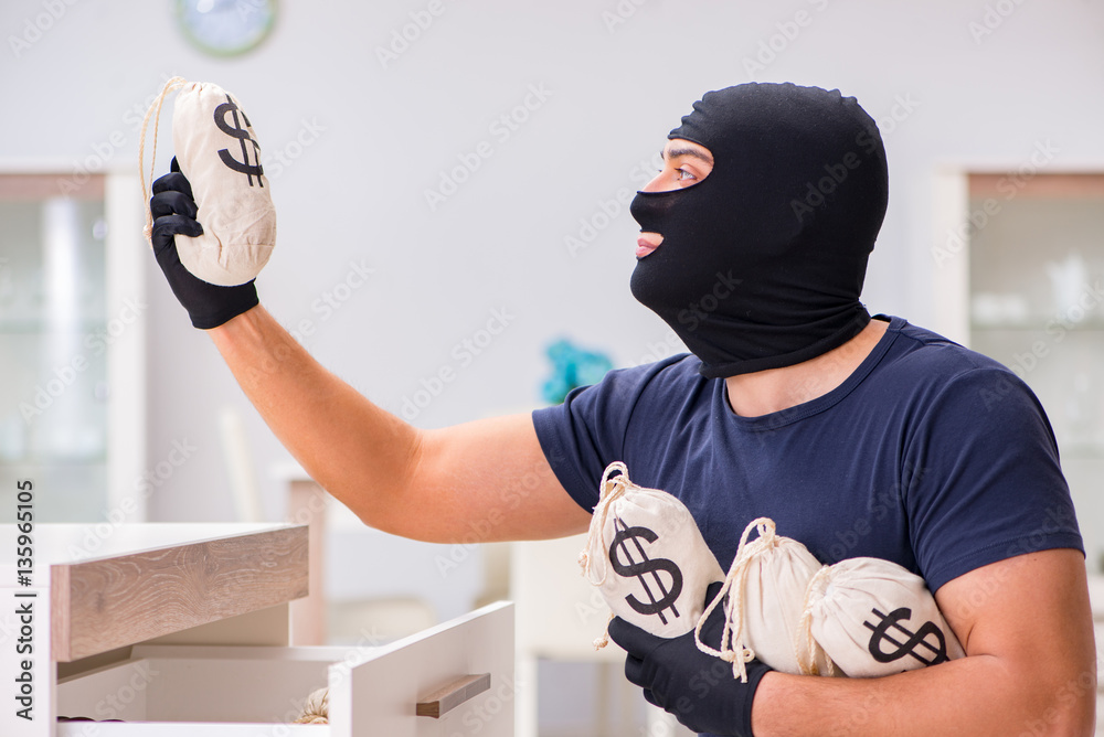 Robber wearing balaclava stealing valuable things Stock Photo | Adobe Stock