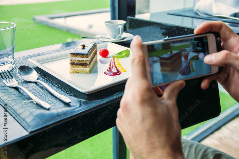 Side view of a man taking a photo of his food in the restaurant ...